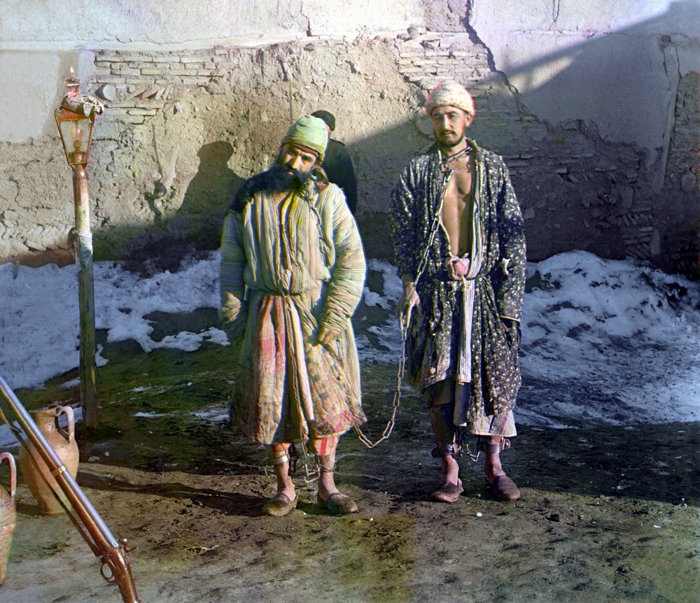 Two prisoners in shackles and a guard behind them, Russian Empire